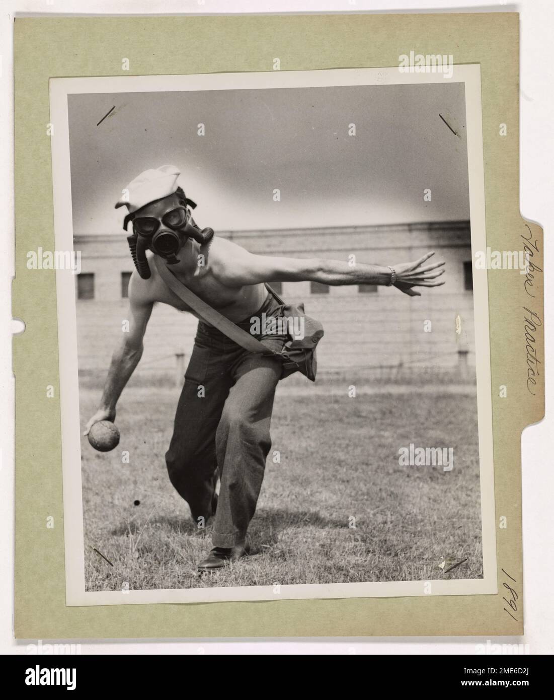 A U.S. Coast Guardsman is shown playing baseball while wearing a gas ...