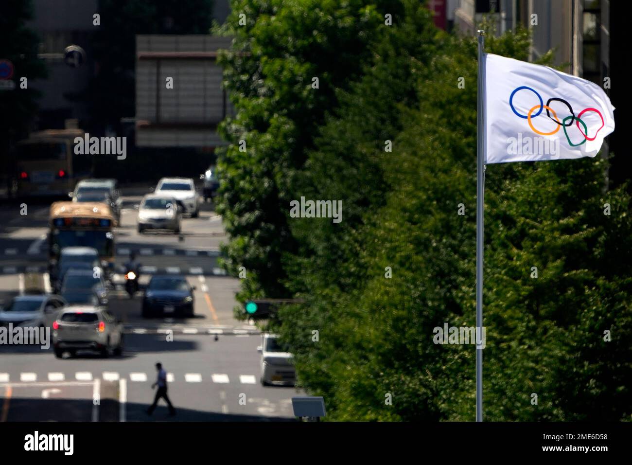 People travel on a nearby street beyond an Olympic flag flying from ...