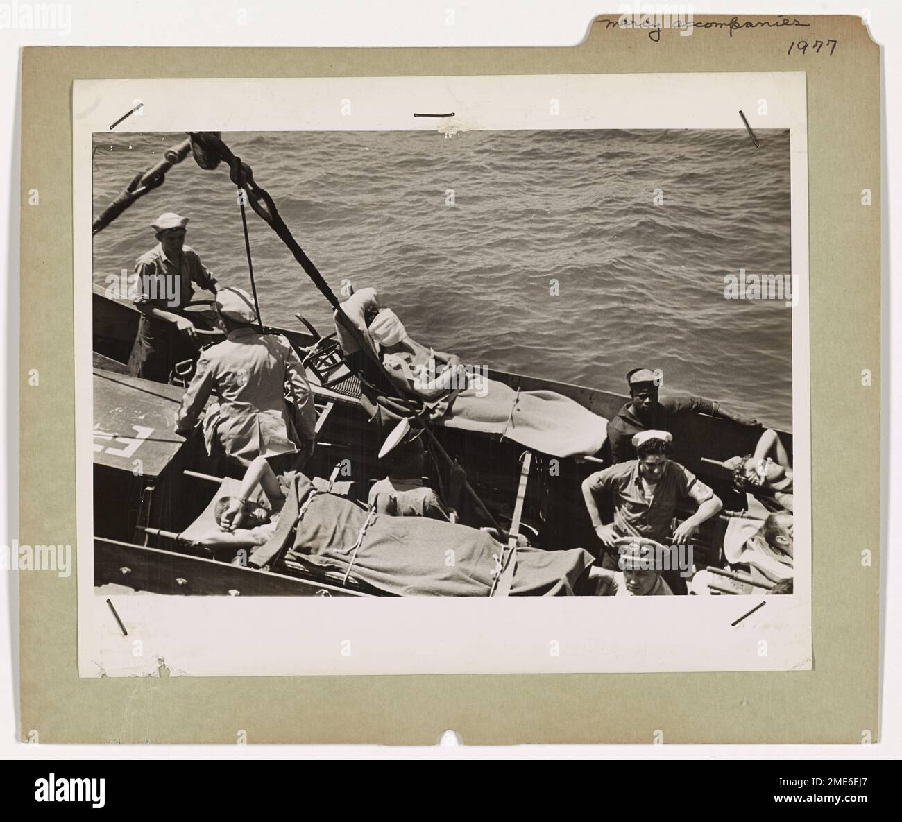 Coast Guardsmen in a landing craft are shown preparing wounded soldiers ...