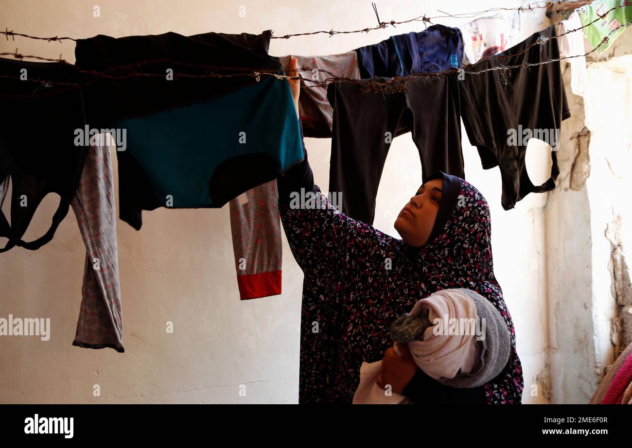 Esraa Nassir, collects her family laundry hanged on Barbed wires inside a damaged room of her ...