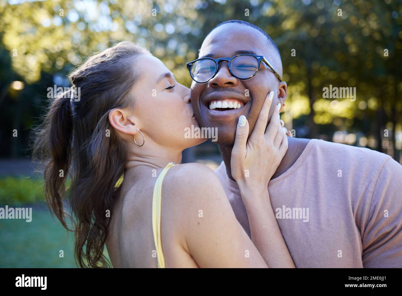 Woman kiss man, happiness and date in park, outdoor in nature with love and commitment in ...