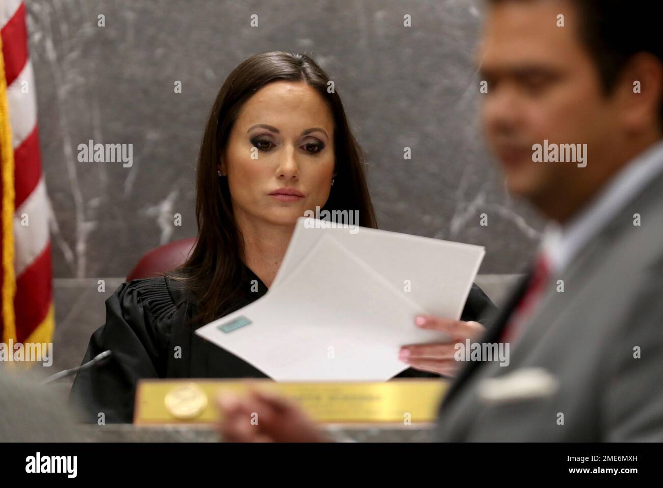 Judge Elizabeth Scherer receives photographs presented as evidence from ...