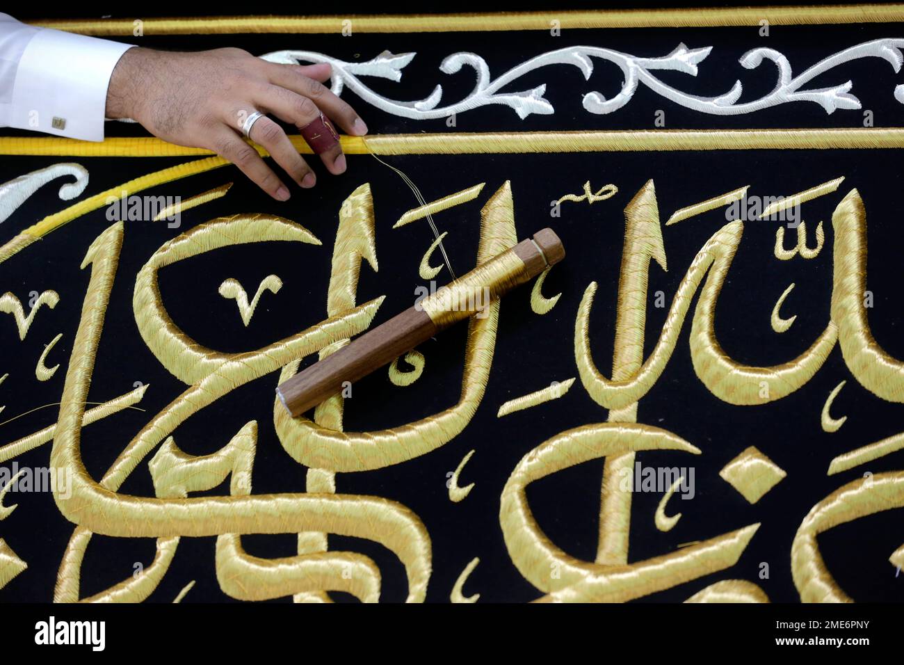 A Saudi worker embroiders Islamic calligraphy using silver threads ...
