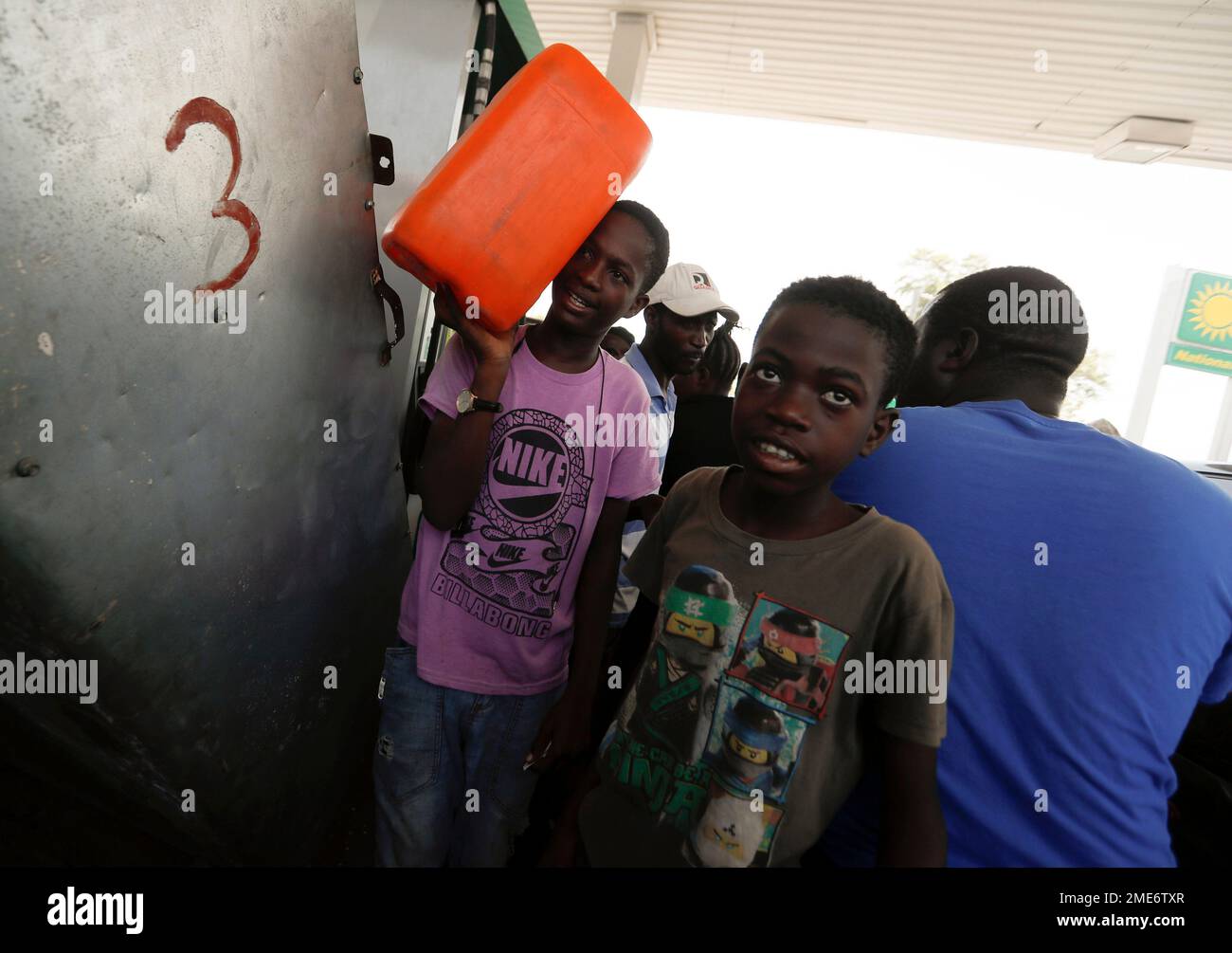 A boy carries a tank of gas as he leaves a gas station in Port-au ...