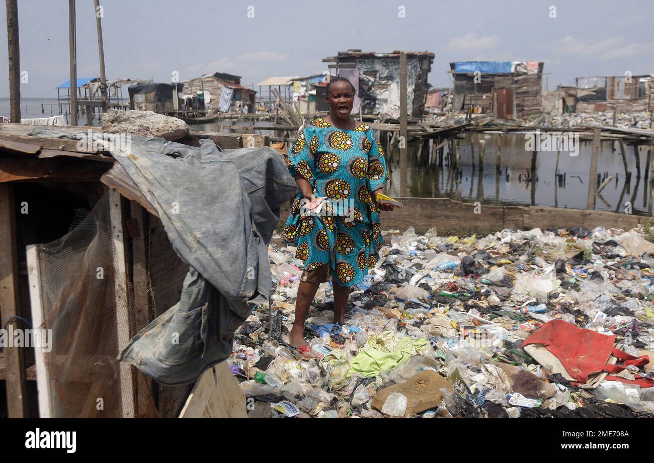 A resident of Oworonshoki Slum gestures outside her house in Lagos ...
