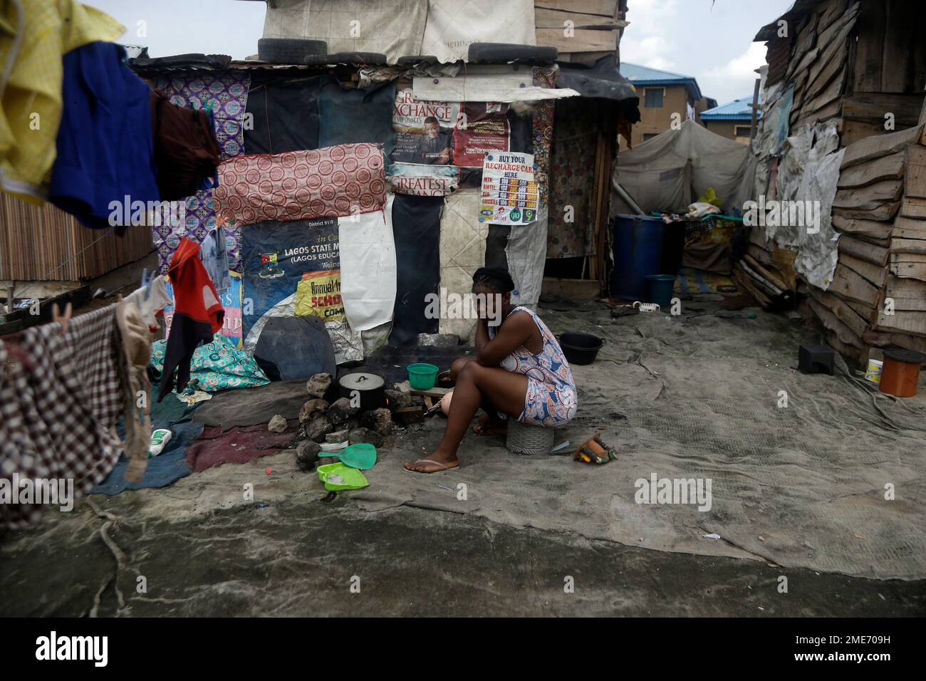 A resident of Oworonshoki Slum prepare a meal outside her house in ...