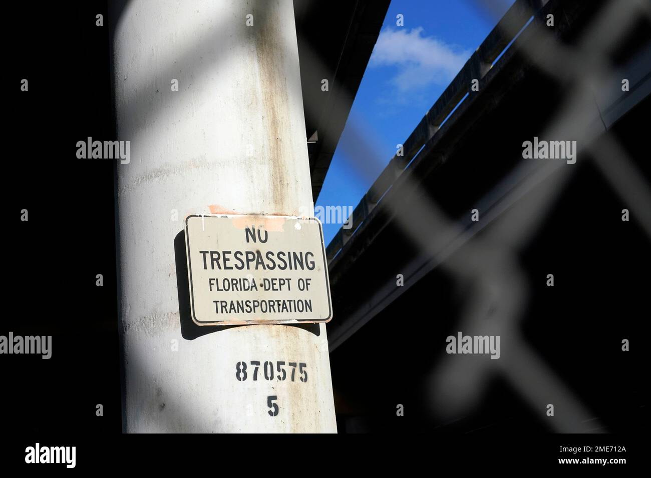 A fence and no trespassing sign are underneath the 1-395 overpass ...