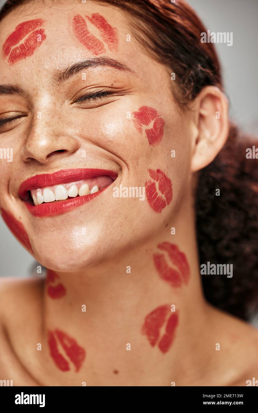Face, red lipstick kiss and makeup on face model woman in studio for cosmetics and happiness ...