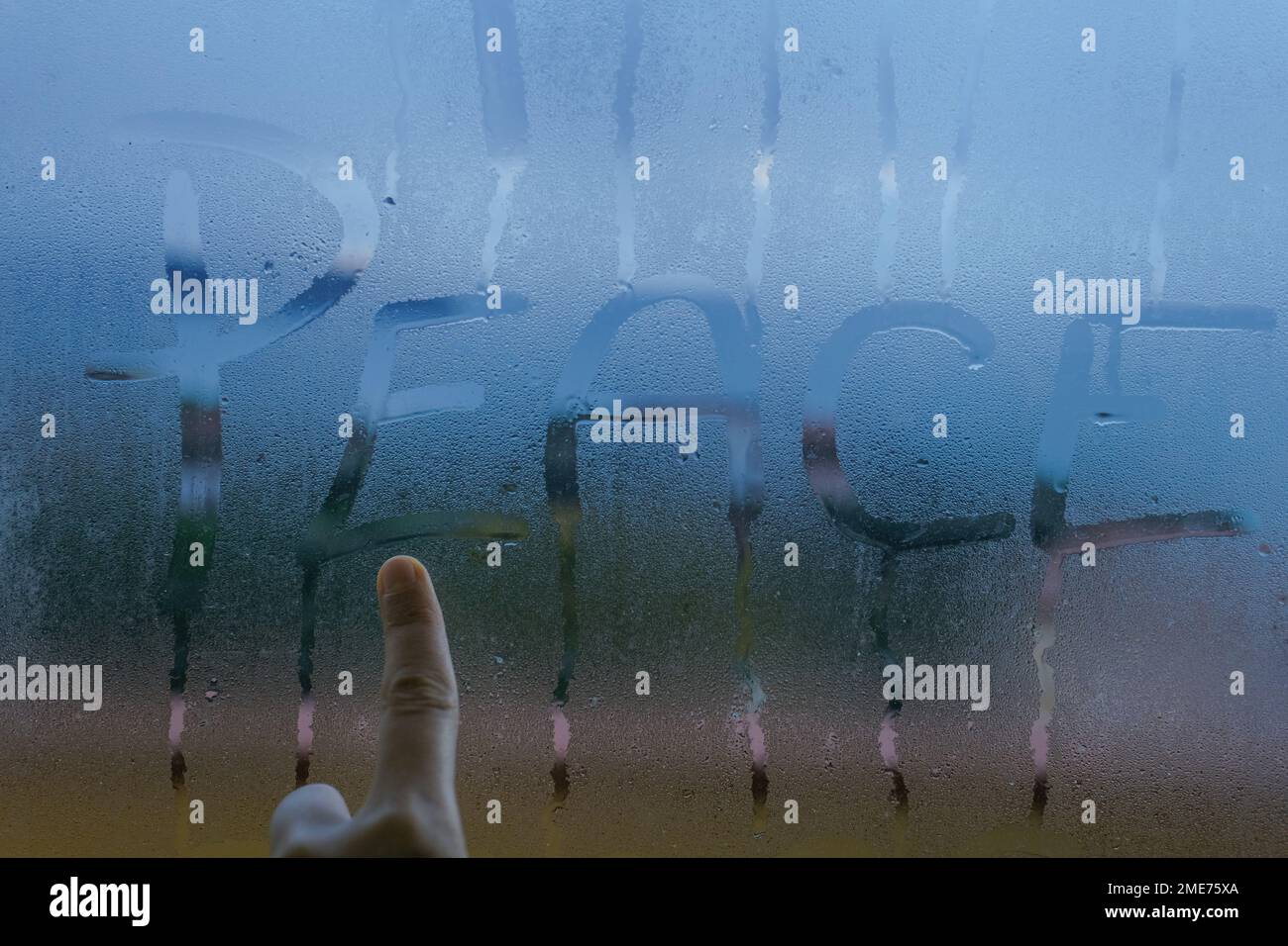 Woman hand writing peace word sign on a foggy window glass, no war ...