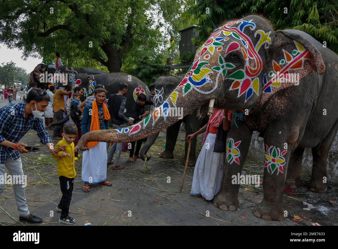 A child offers money to an elephant as a man holds him on the eve of ...