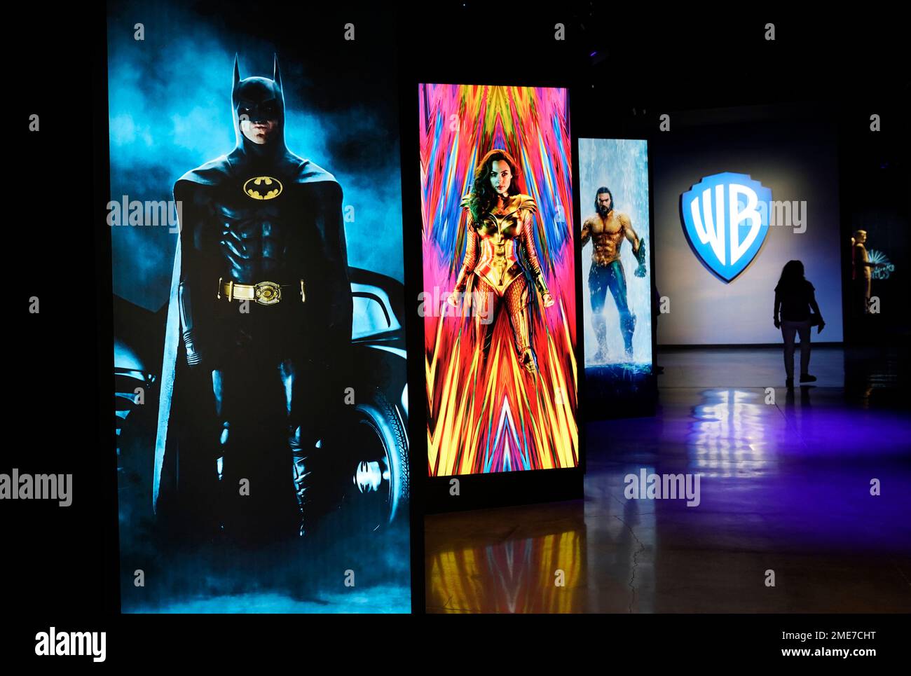 A visitor walks past portraits of DC Comics superheroes as she enters ...