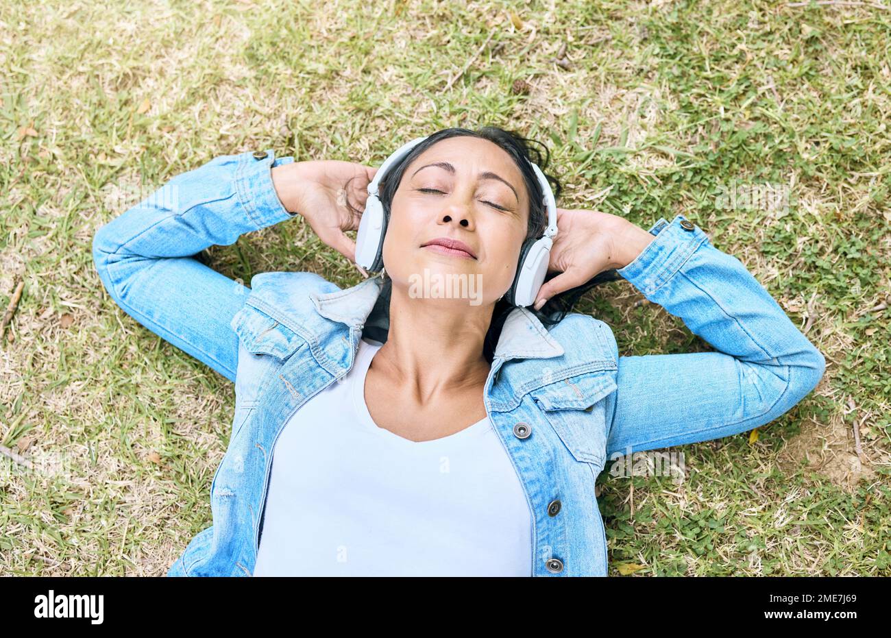 Music, headphones and woman relax in a park, peace and zen from above ...