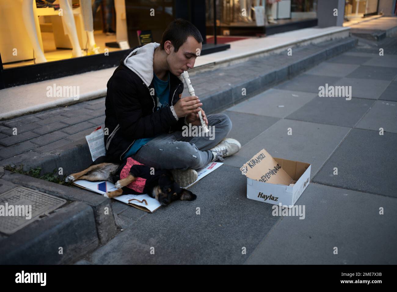A man plays a recordere to make some money on a sidewalk in the Turkish ...