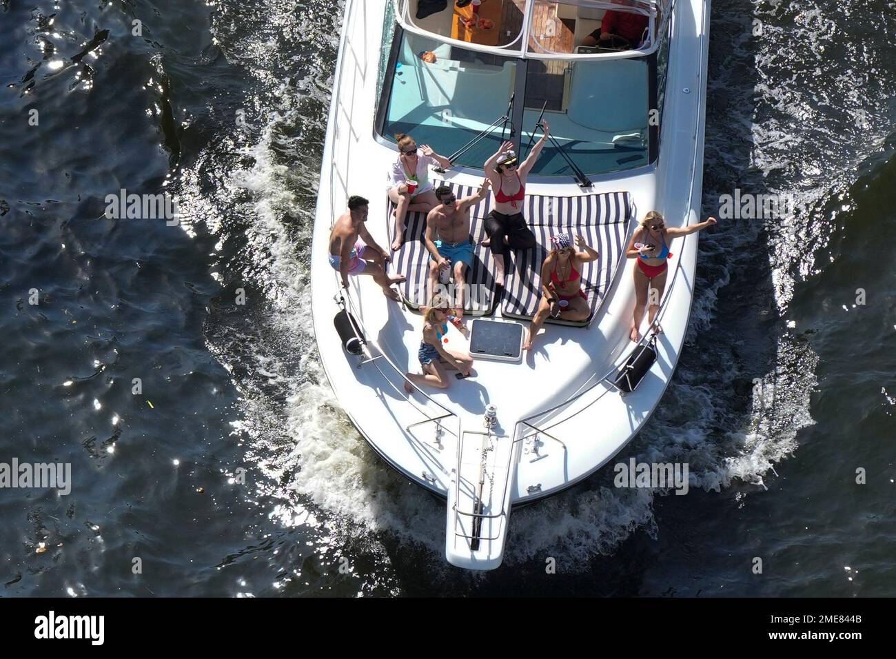Revelers cheer as they pass another boat, as powerboats ply the Miami ...