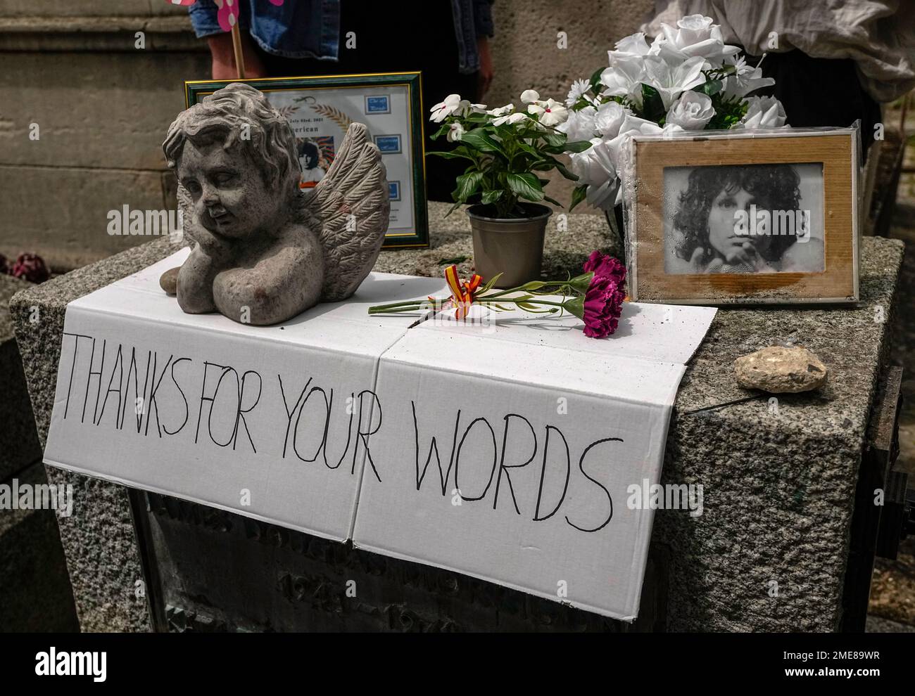 A placard, flowers and pictures are displayed on the tomb of rock ...
