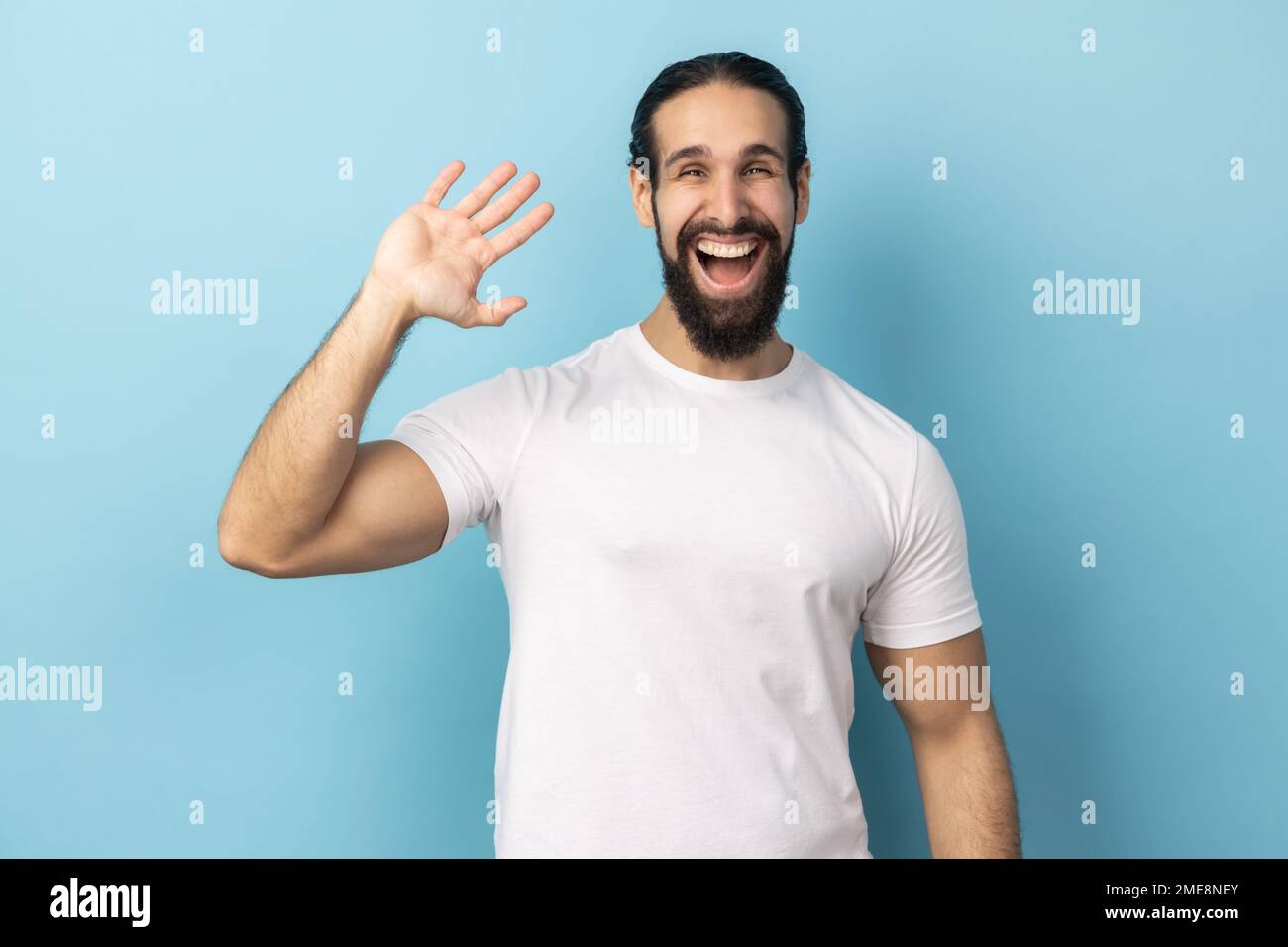 Portrait of positive man with beard wearing white T-shirt standing with ...