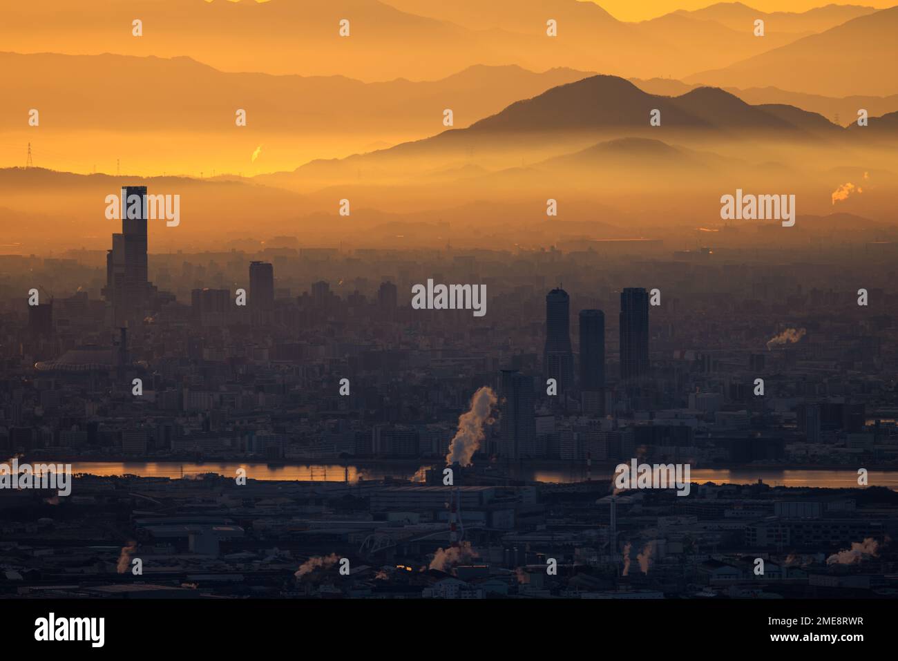 Orange haze from industrial emissions in city by river and mountains at ...
