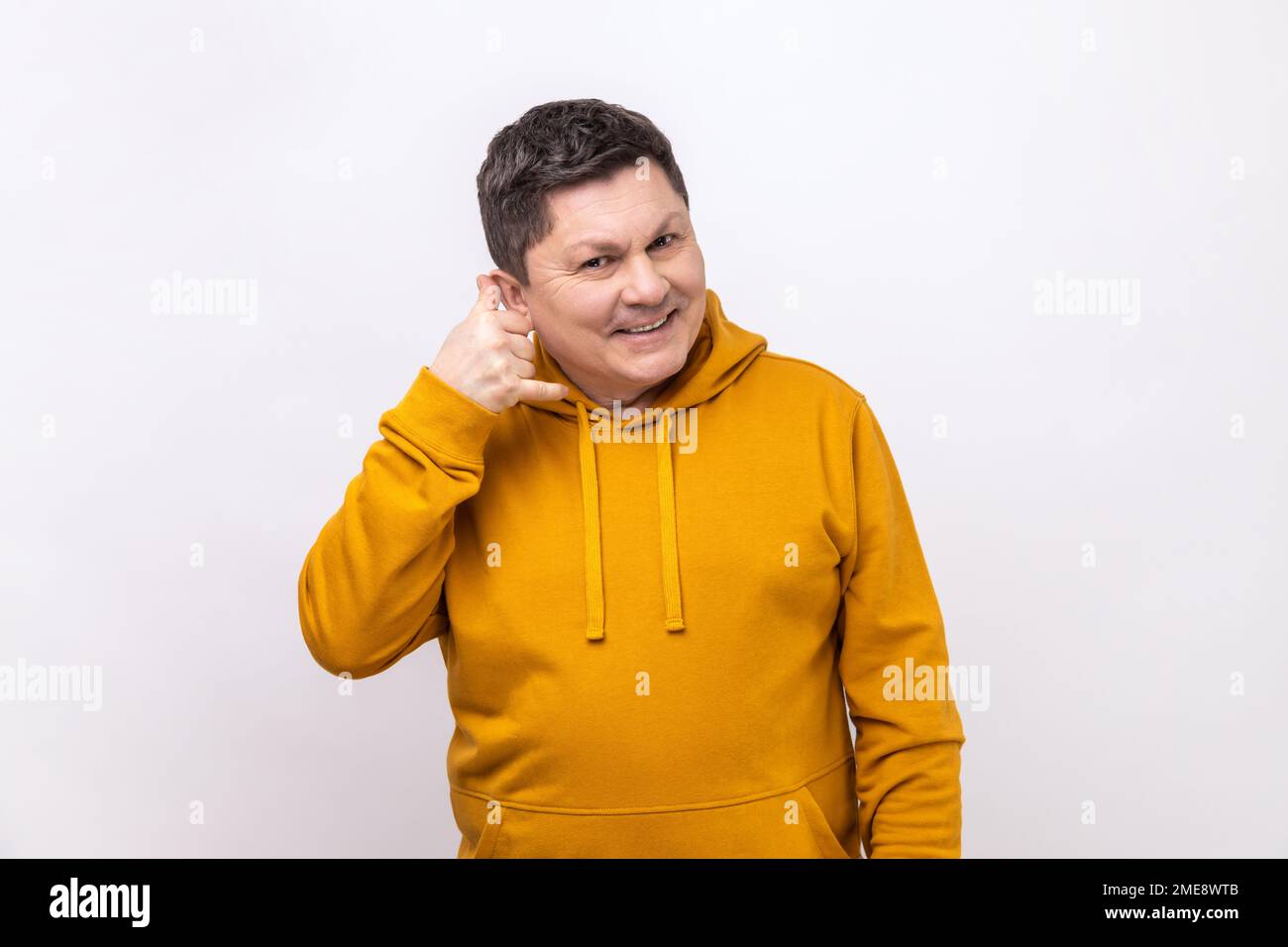 Portrait of handsome cheerful man holding telephone hand gesture near ...