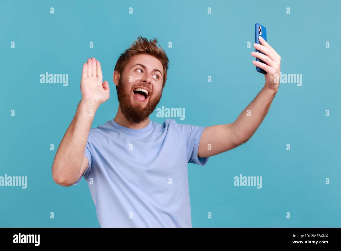 Portrait of positive optimistic bearded man talking on video call and ...