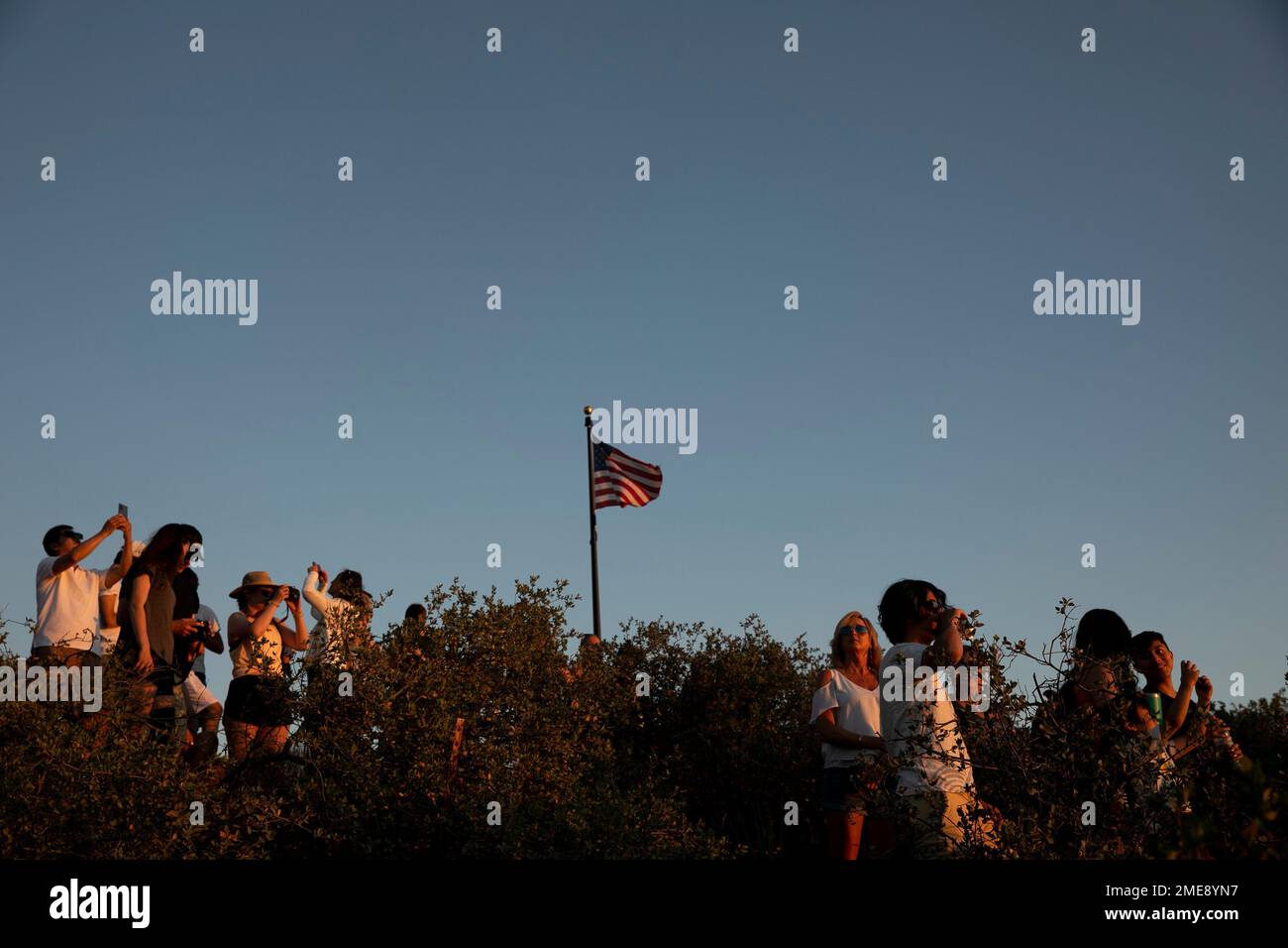 An American flag flies as people watch the sun set from the Sedona ...