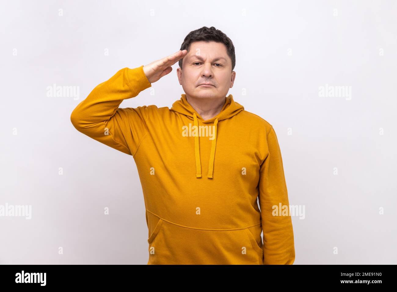 Subordinate man saluting, holding hand near head, looking at camera ...