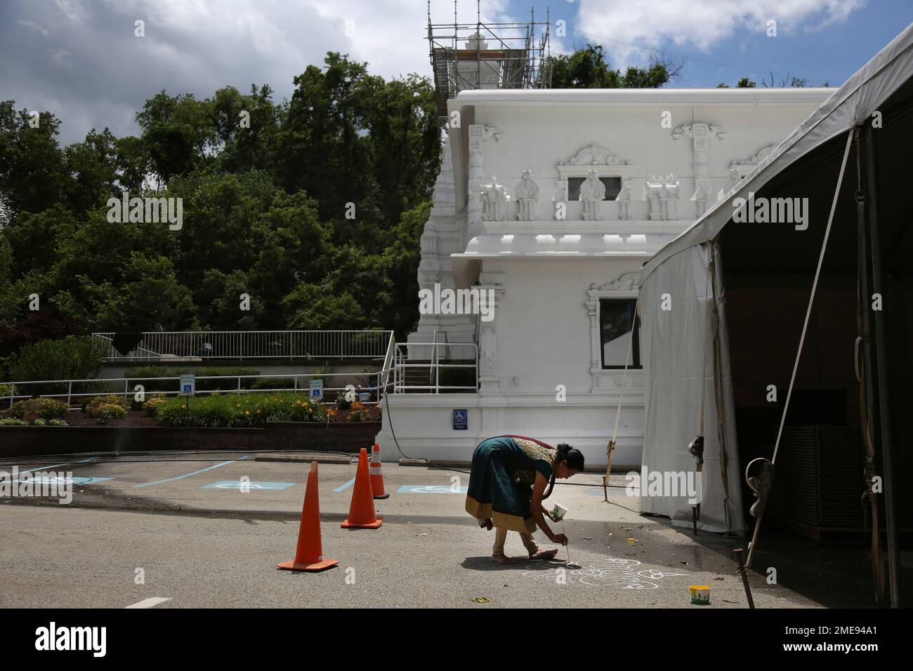 Sudha Krishnasamy paints on the pavement outside of a ritual tent ...