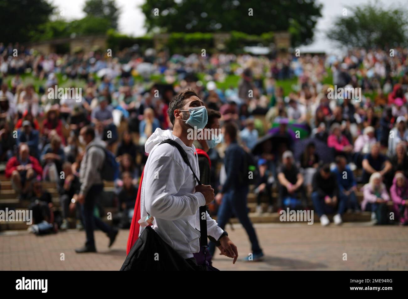 A man wearing a face mask walks past spectators on day one of the ...