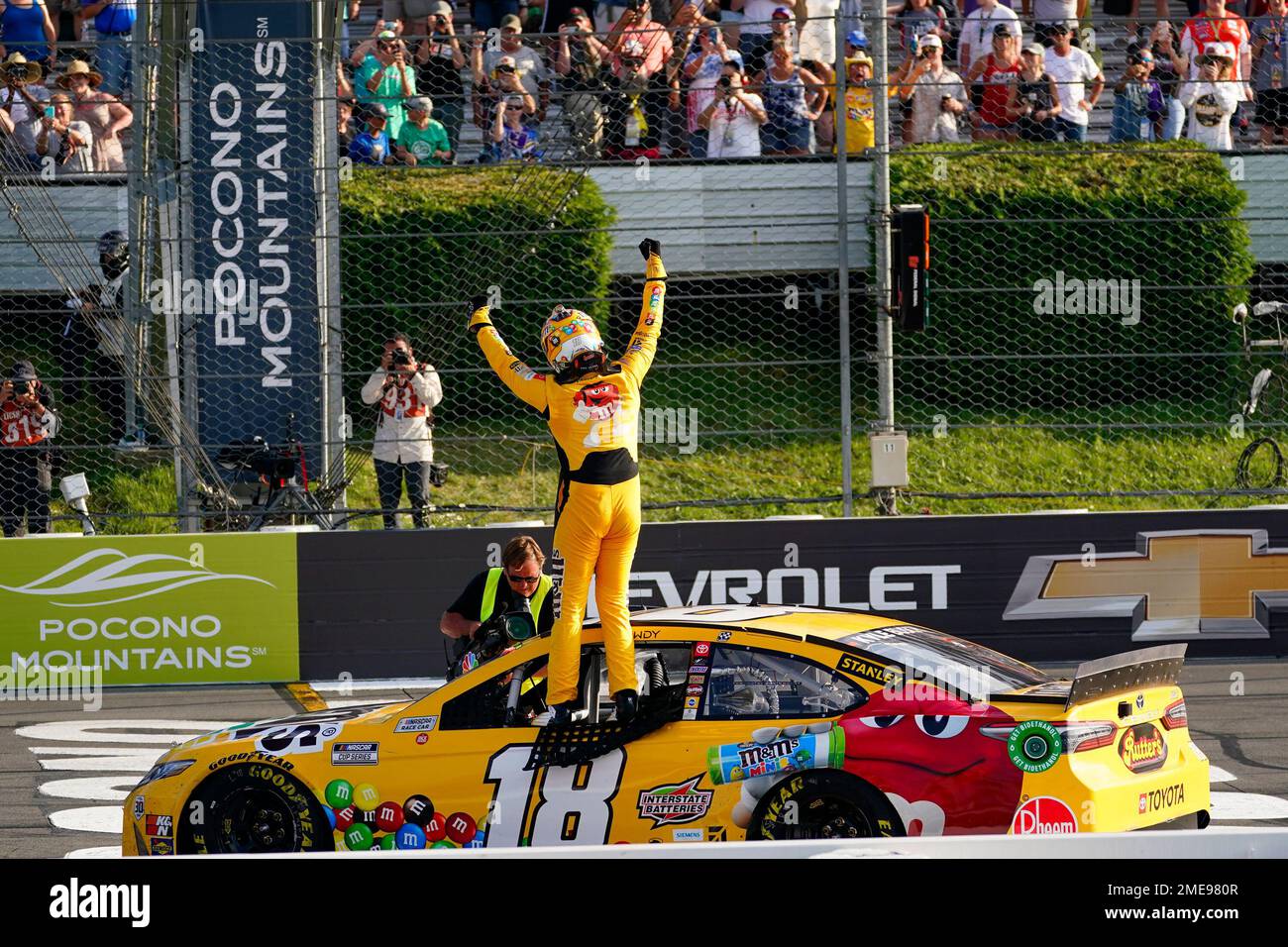 Fans cheer as Kyle Busch stands on the window opening of his race car ...