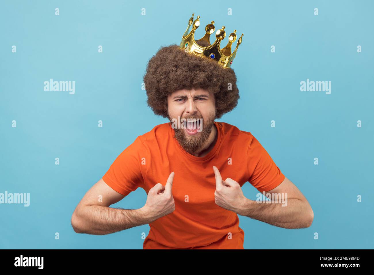 Portrait of crazy man with Afro hairstyle in golden crown and pointing ...
