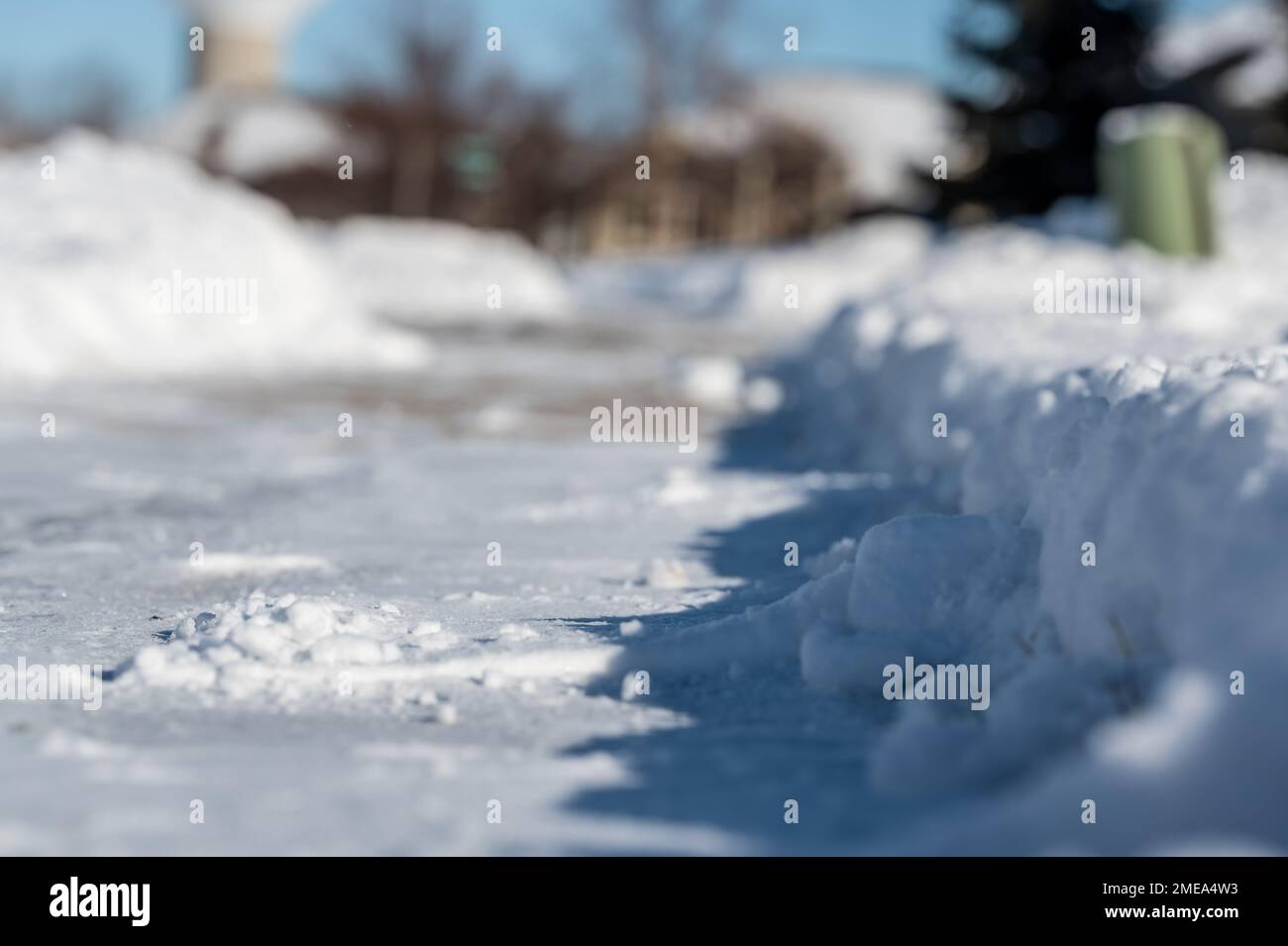 Selective focus ground level view of snow blown sidewalk section with ...