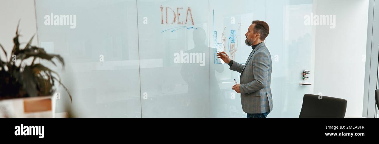 Adult businessman writing notes on the white board Stock Photo - Alamy