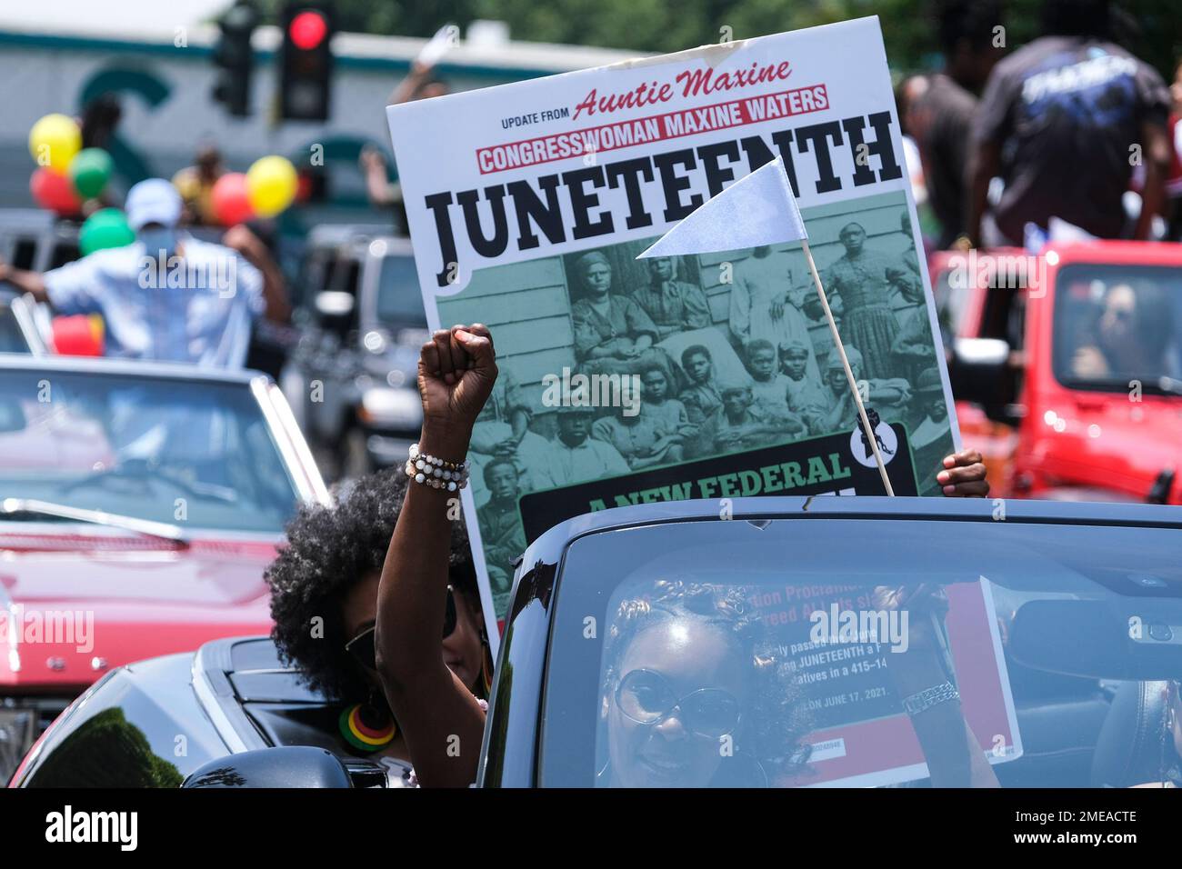 People hold a sign in their car during a car parade to mark Juneteenth ...