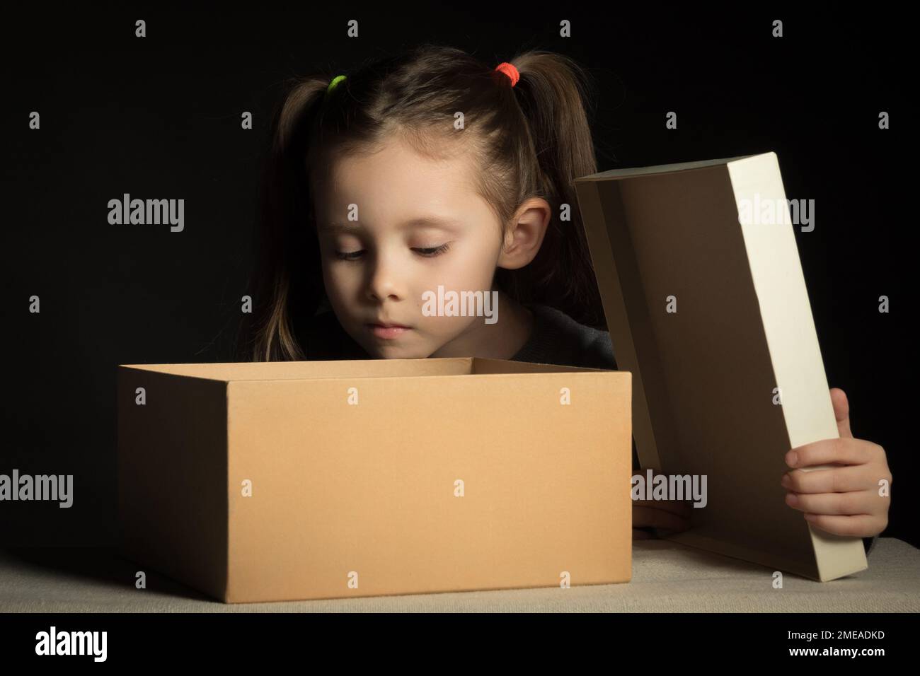 Sad and disappointed little girl opens a long-awaited package with a ...