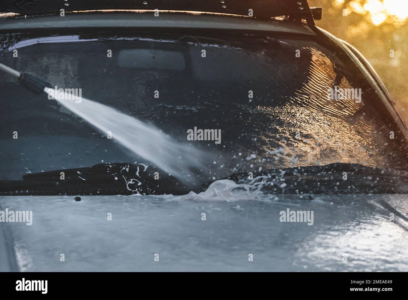 Washing car windshield with high-pressure water hose on car wash ...