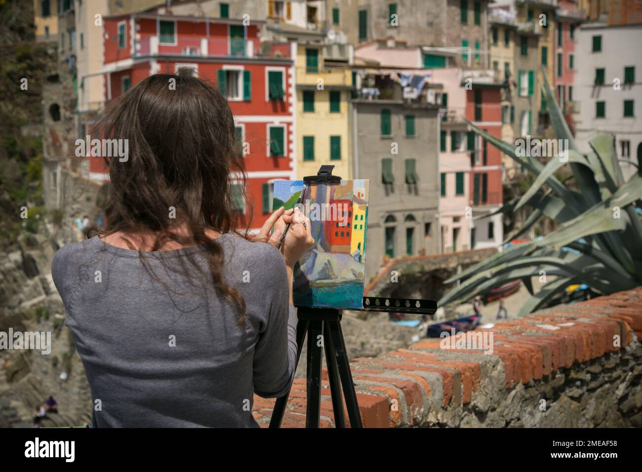 Young woman set up with an easel painting a picture of the buildings in ...
