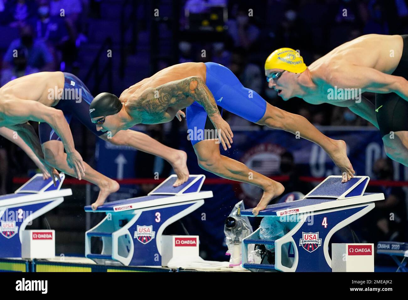 Caeleb Dressel, center, dives at the start of the men's 100-meter ...