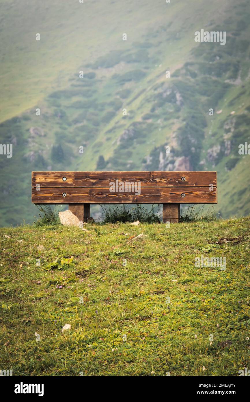 Wooden bench with a view of the mountains in a touristic hiking trail ...