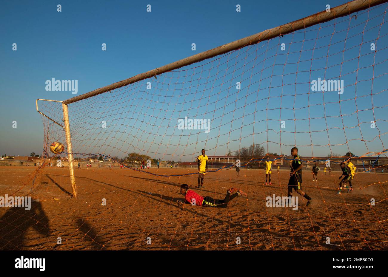 Soccer players play a friendly match on a dusty soccer field in Soweto ...