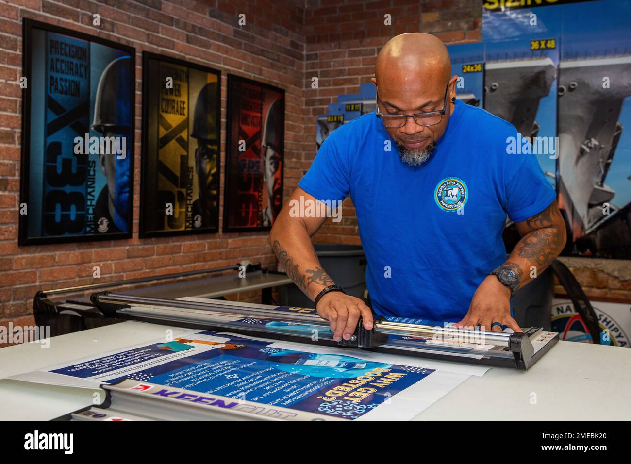 Visual Information Specialist Lorenzo Raines cutting a laminated ...