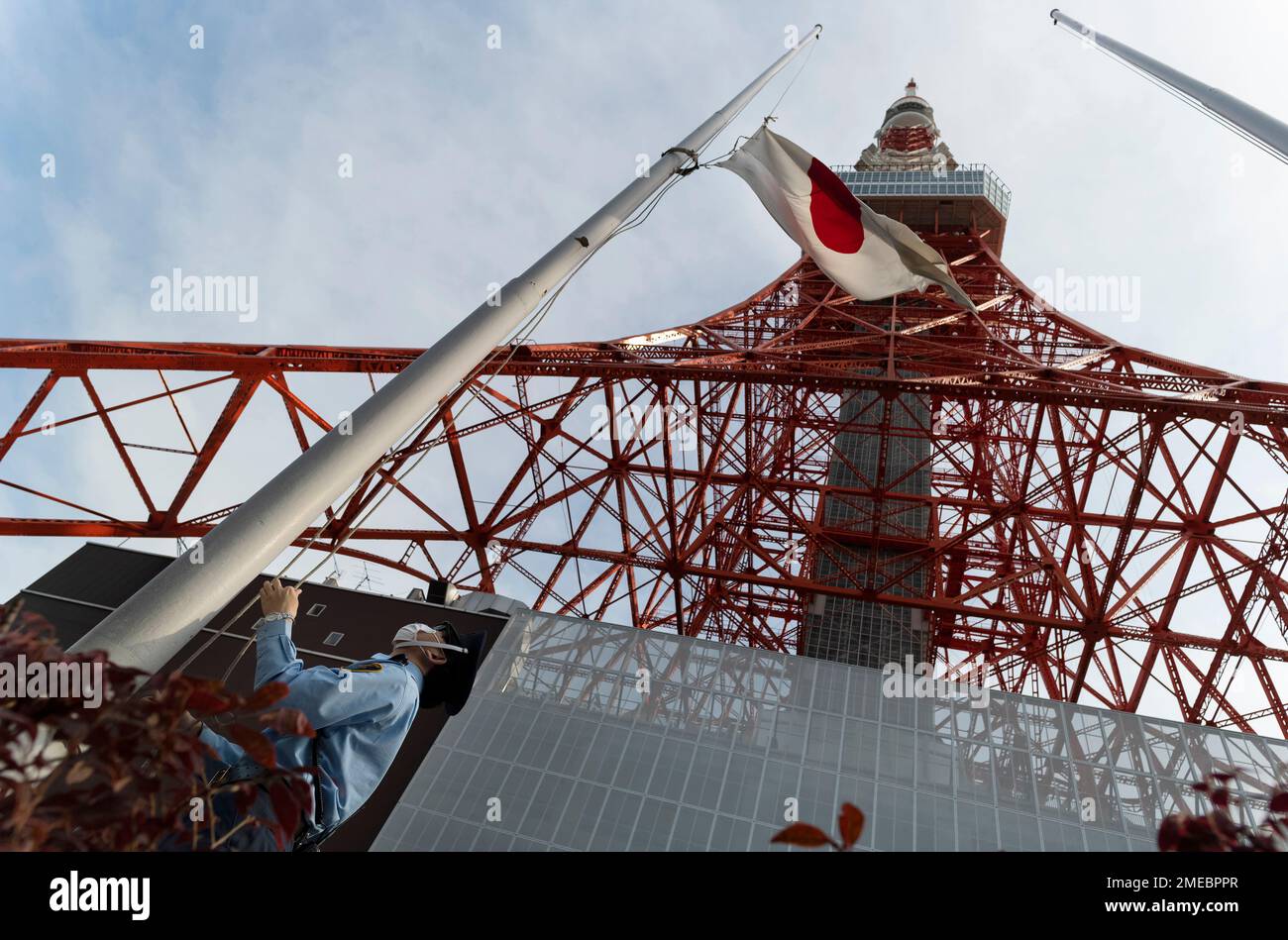 A security guard works on his daily routine of lowering the Japanese flag at the Tokyo Tower in ...