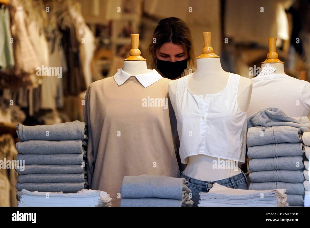 A worker wears a mask while straightening up a display amid the COVID ...