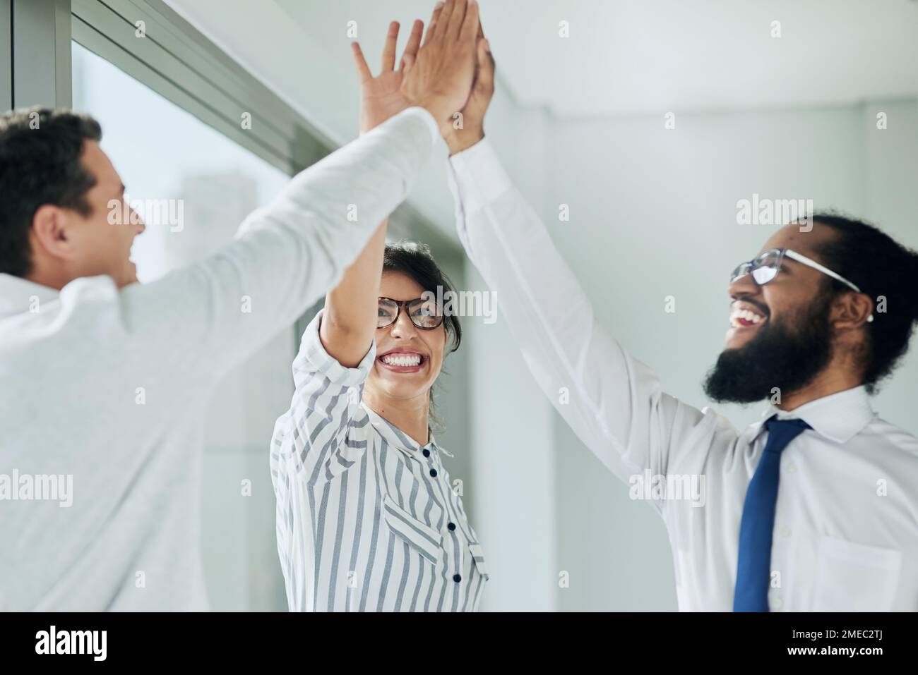 Teamwork is a powerful force. a group of businesspeople high fiving ...
