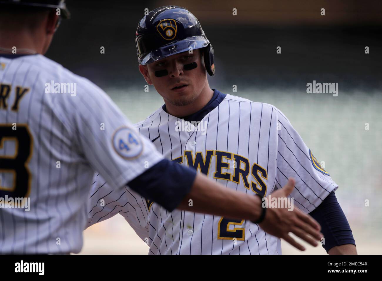 Milwaukee Brewers' Luis Urias is congratulated by first base coach ...