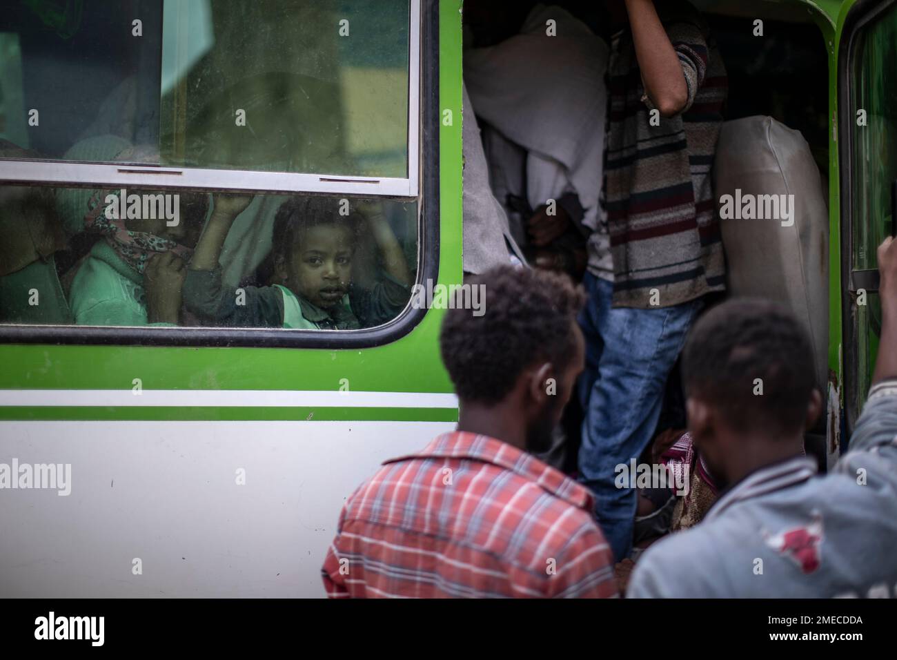 A young child looks out from the window of a departing bus in the town ...
