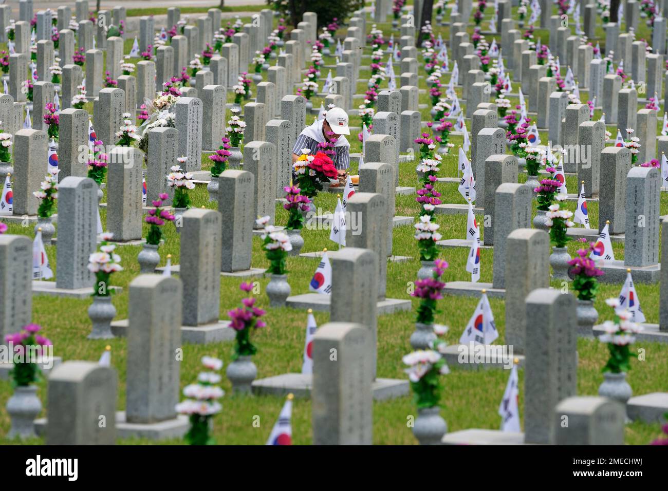 South Korean Cho Duk-ryong sits in front of the gravestone of his ...