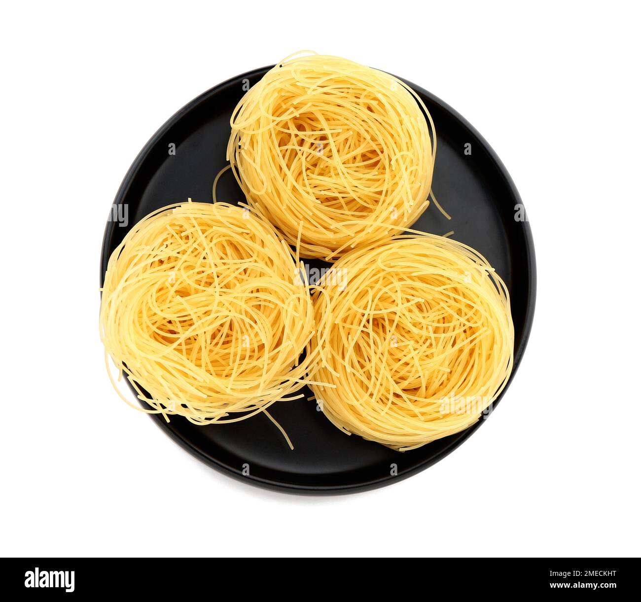 Plate of raw pasta nests on white background Stock Photo - Alamy