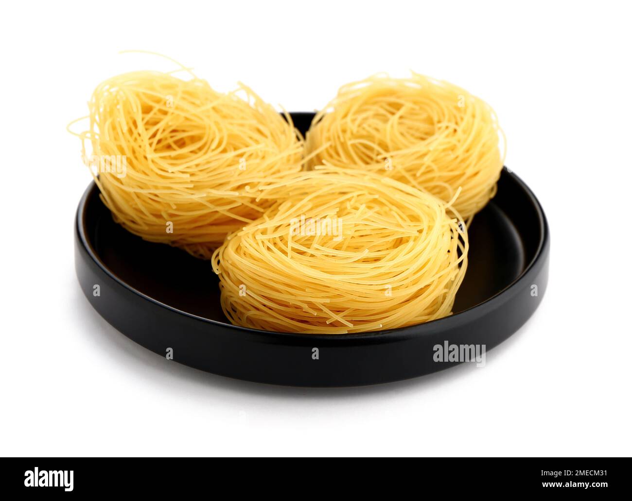 Plate of raw pasta nests on white background Stock Photo - Alamy