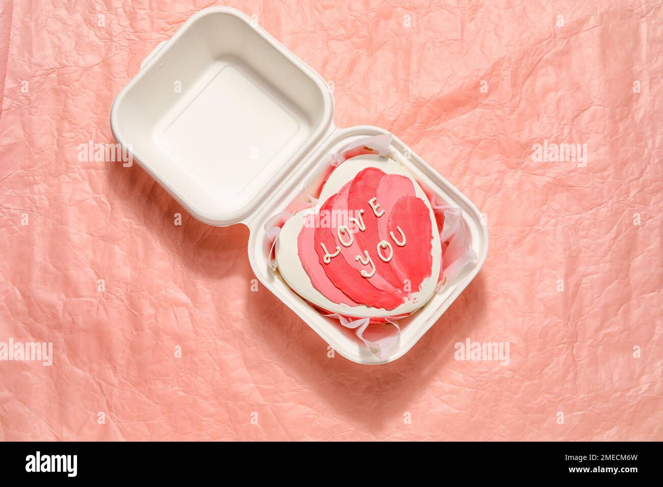 Plastic lunch box with heart-shaped bento cake on pink background ...
