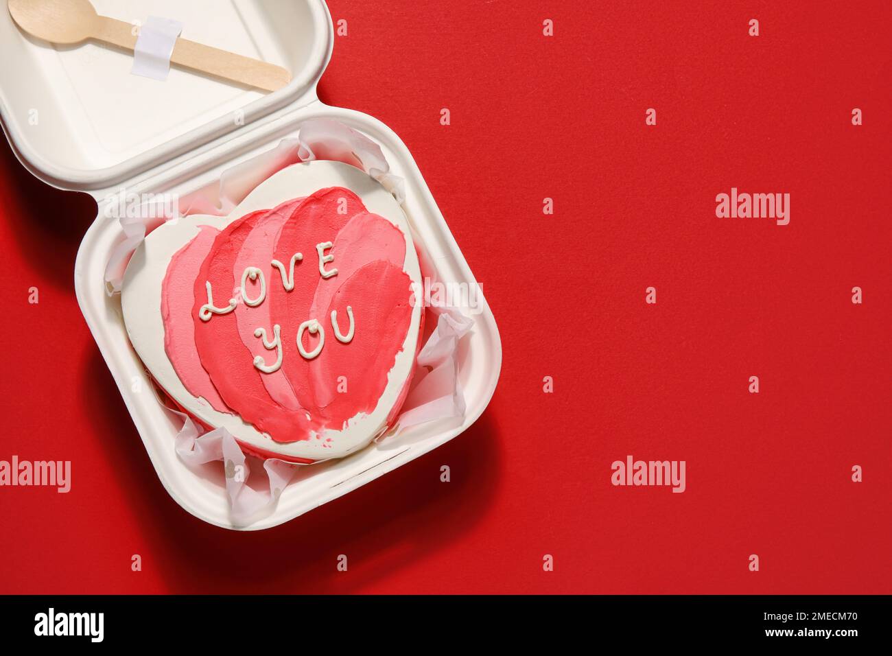 Plastic lunch box with heart-shaped bento cake on red background ...