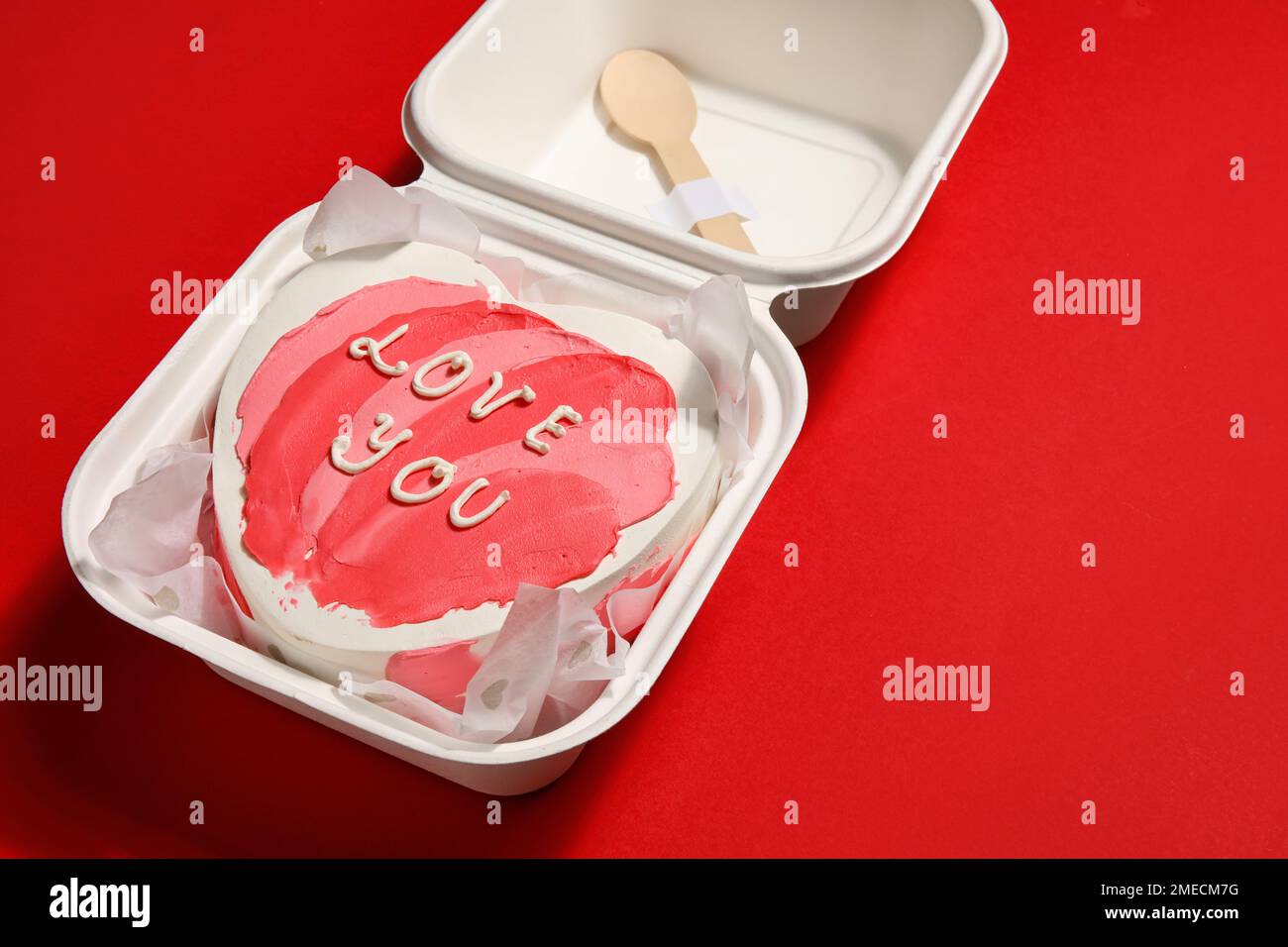 Plastic lunch box with heart-shaped bento cake on red background ...